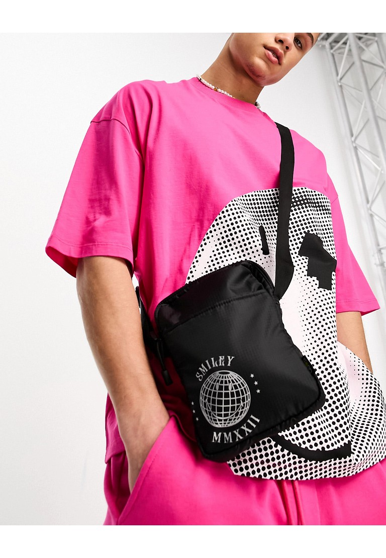 ASOS DESIGN Smiley Collab cross body flight bag with metallic logo in black